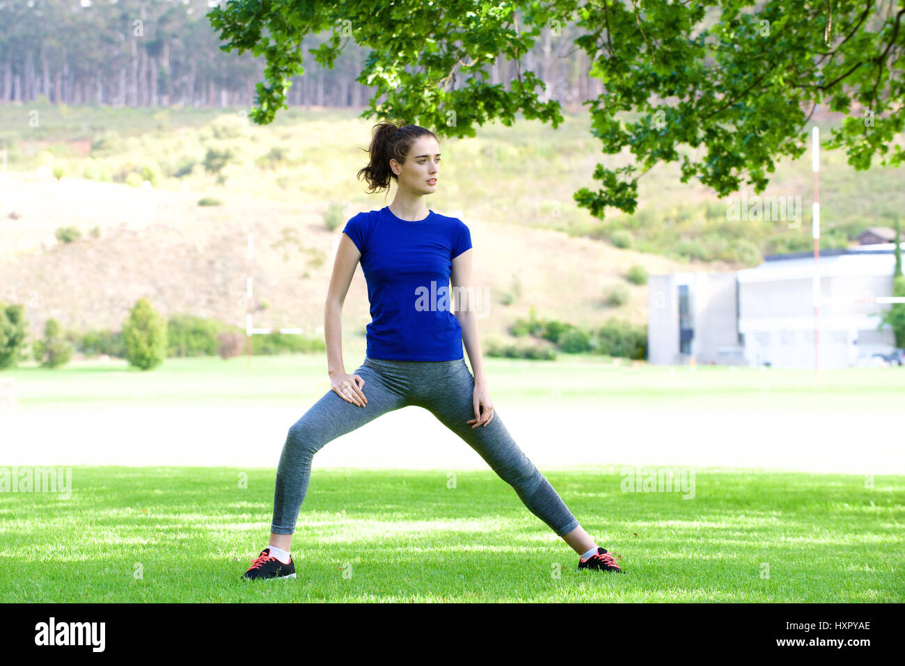 Full length portrait of serious woman stretching outside in summer ...