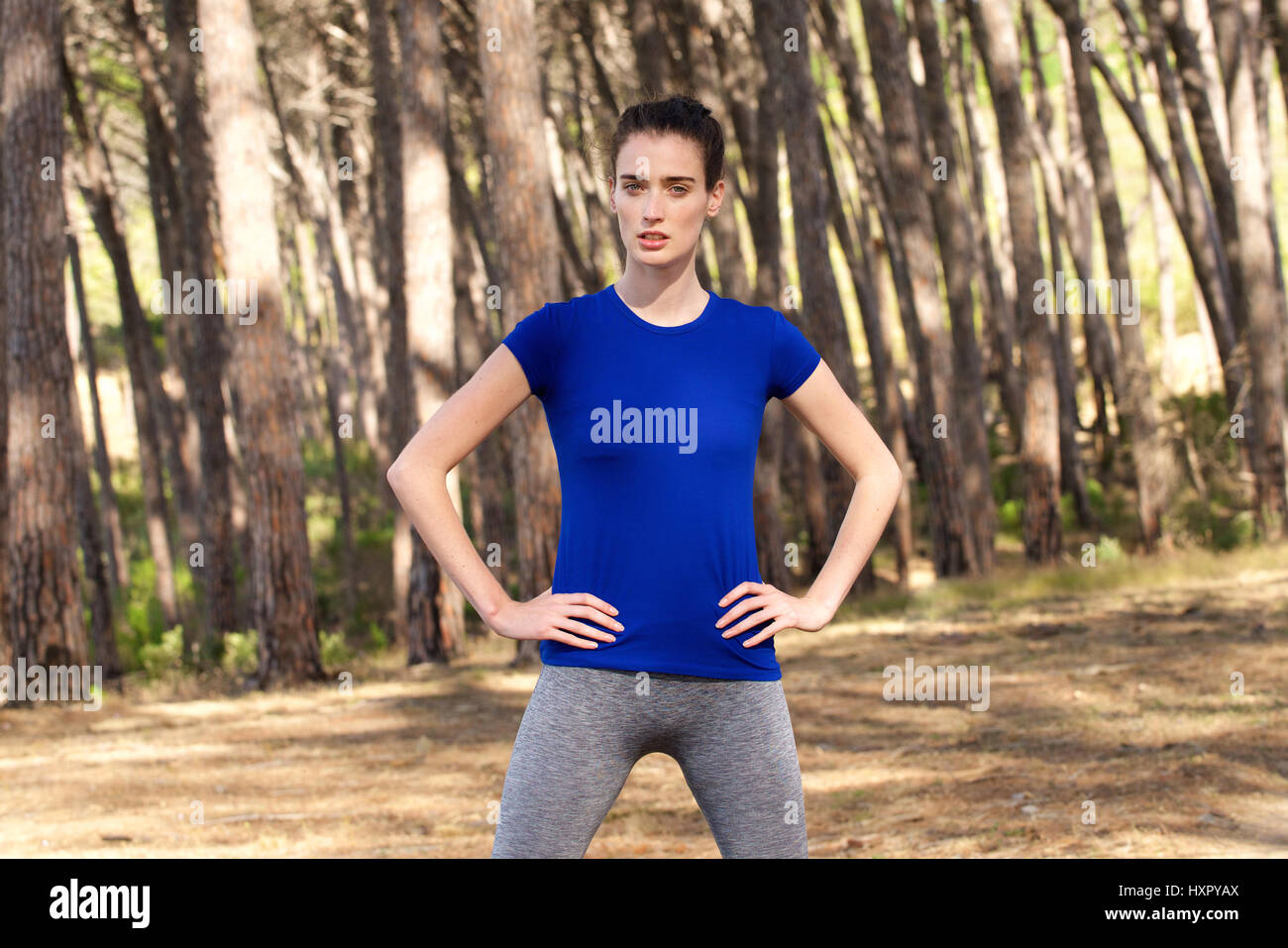 Portrait of confident sporty woman with both hands on hips standing in ...