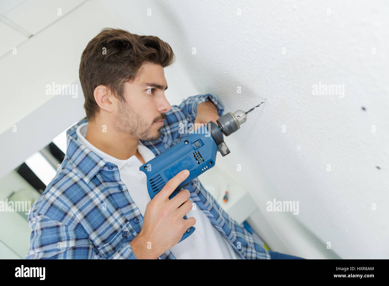male builder drilling holes in wall at construction site Stock Photo ...