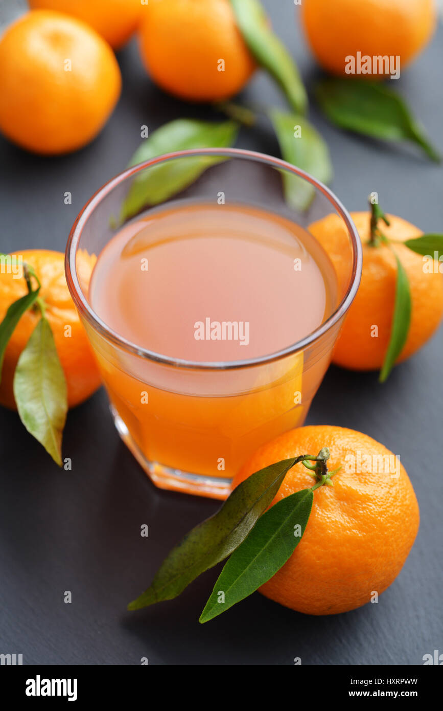 Citrus juice in glass and fresh mandarin orange on slate background ...