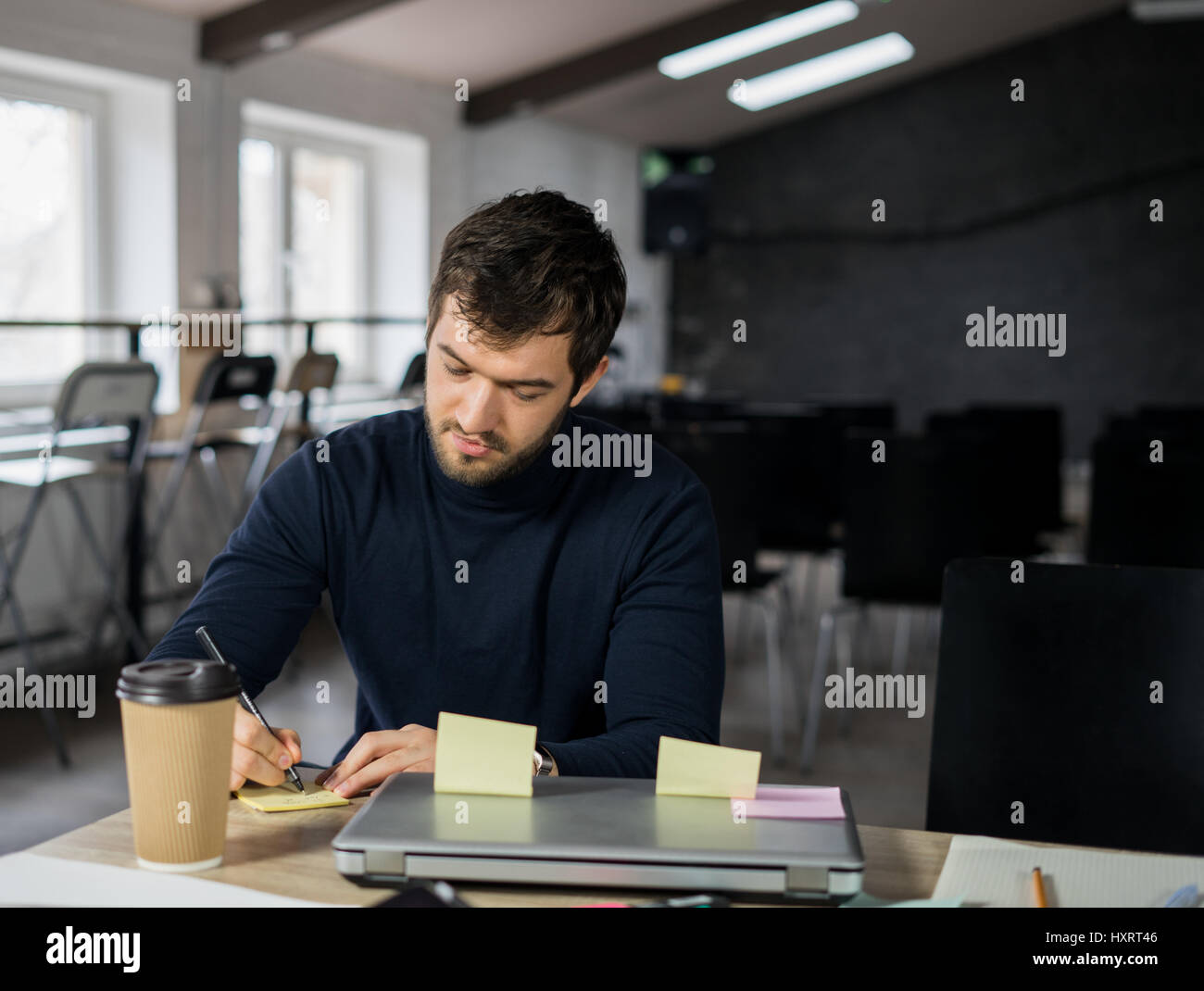 Busy bearded student man is writing on paper sticker notes his planning ...