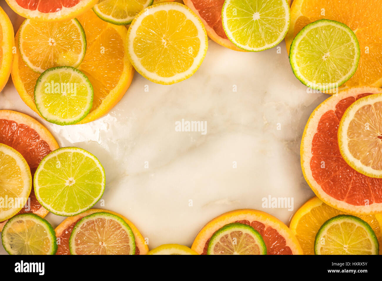 A vibrant frame made up of juicy citrus fruits, on a white marble ...