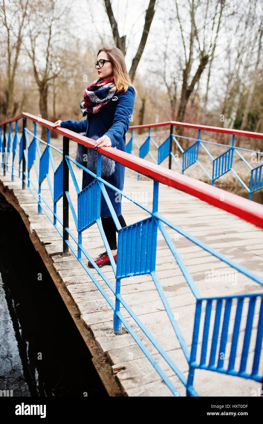 Young hipster girl wear on coat,scarf and glasses stay on small bridge ...