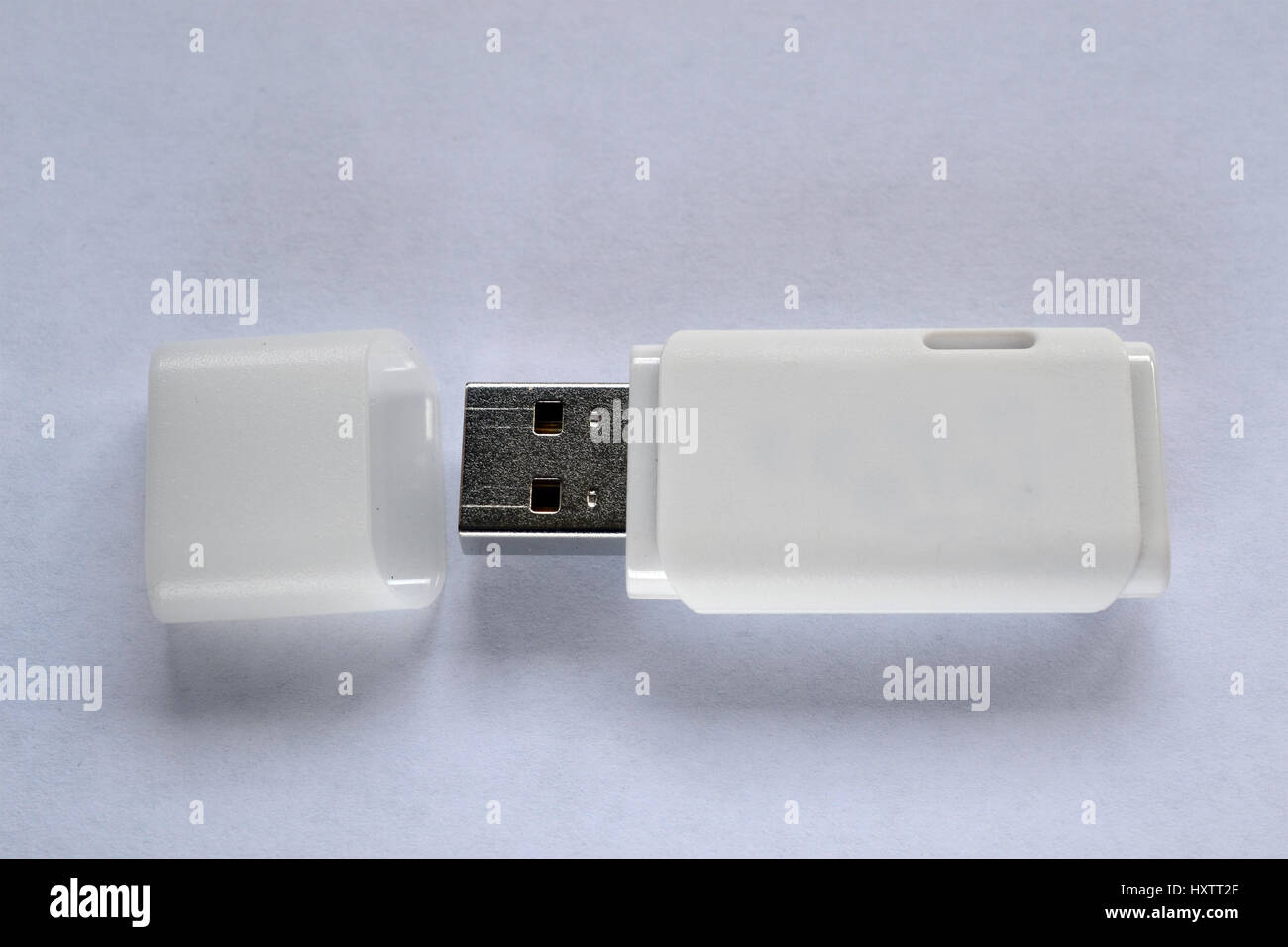 A white USB memory stick on a white piece of paper, with the lid off ...