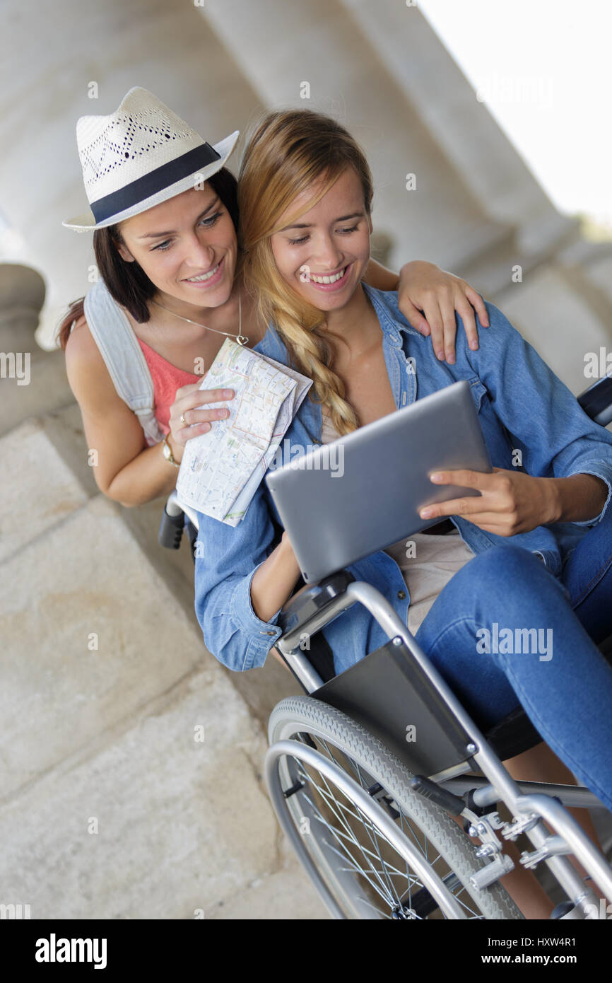 two friends visiting foreign city one sitting in wheelchair Stock Photo ...