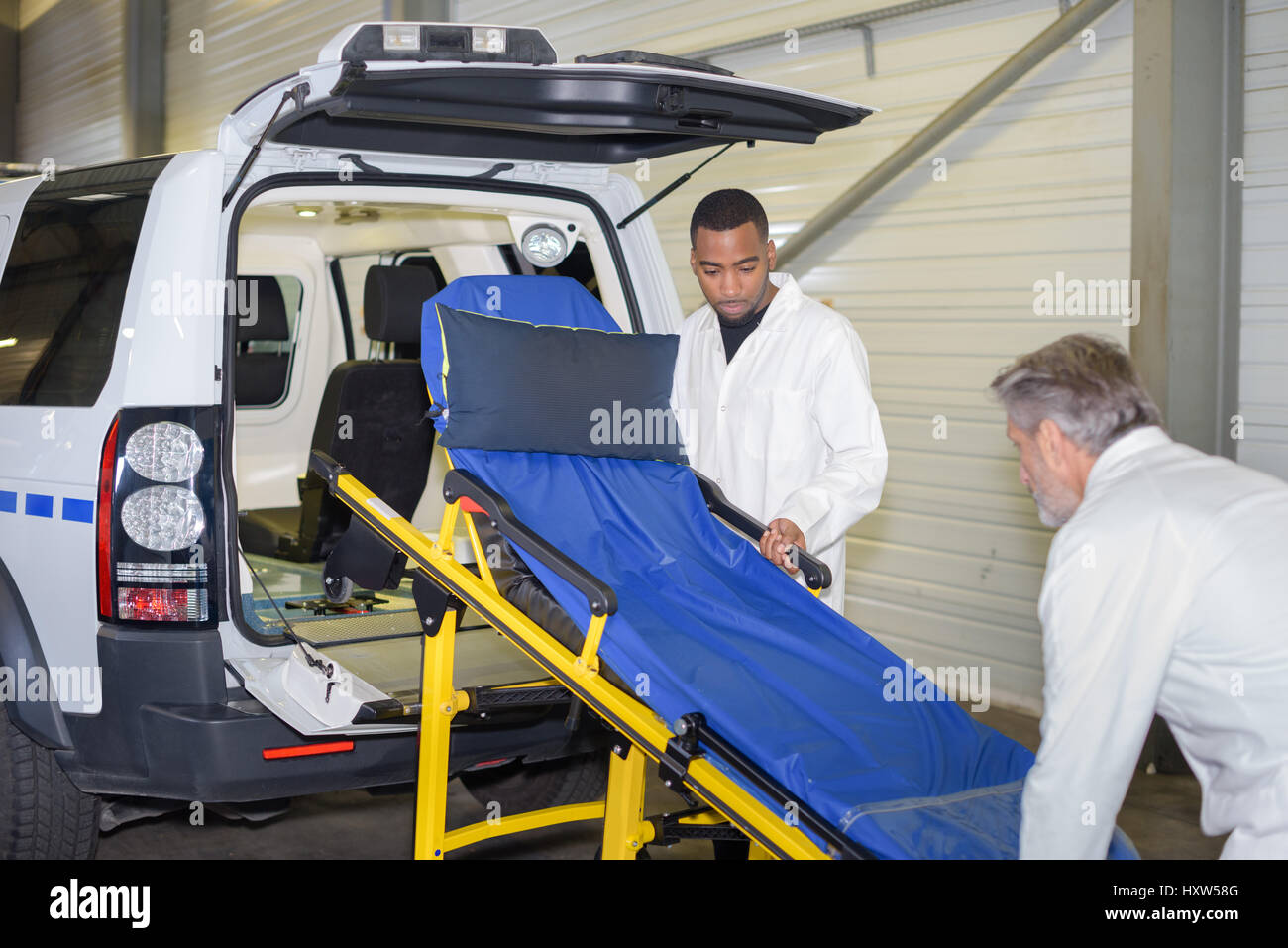 Paramedics loading stretcher into emergency vehicle Stock Photo - Alamy