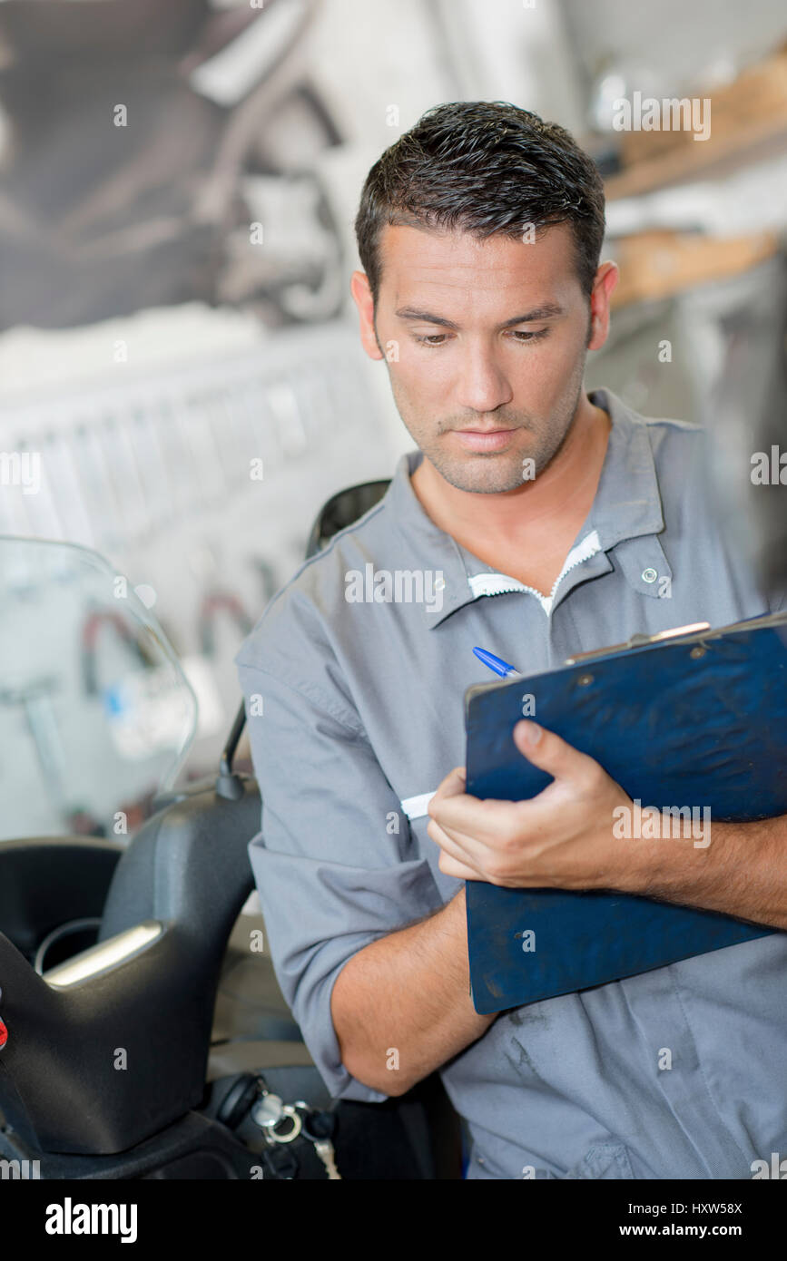 Mechanic making notes on clipboard Stock Photo - Alamy