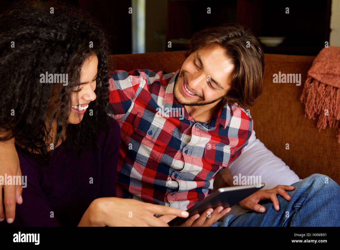 Portrait of a happy young couple relaxing at home with digital tablet ...