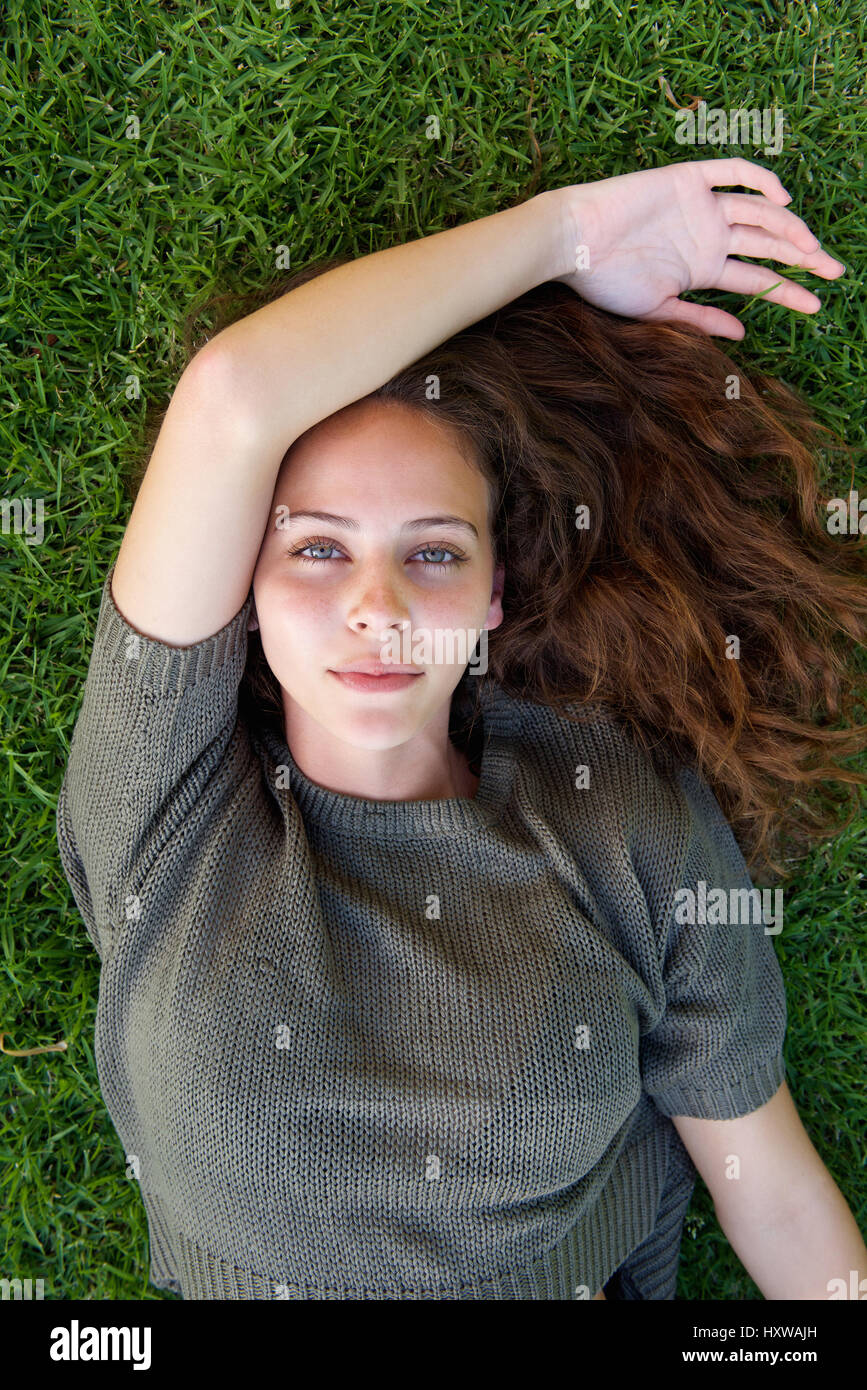 Portrait of beautiful young model staring while lying on grass Stock ...