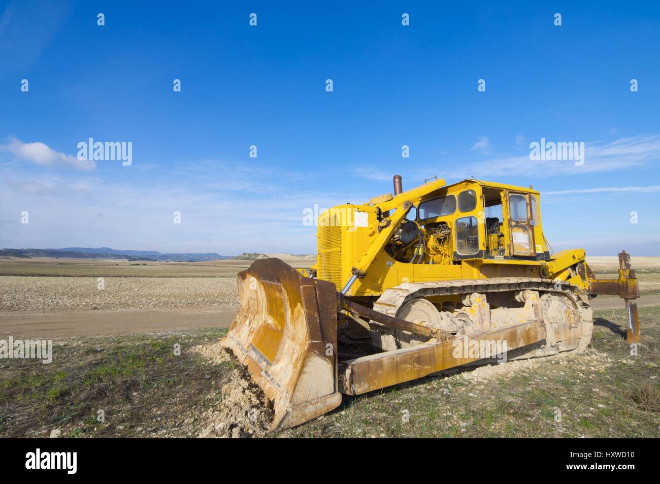 Yellow bulldozer in a field with blue sky Stock Photo - Alamy