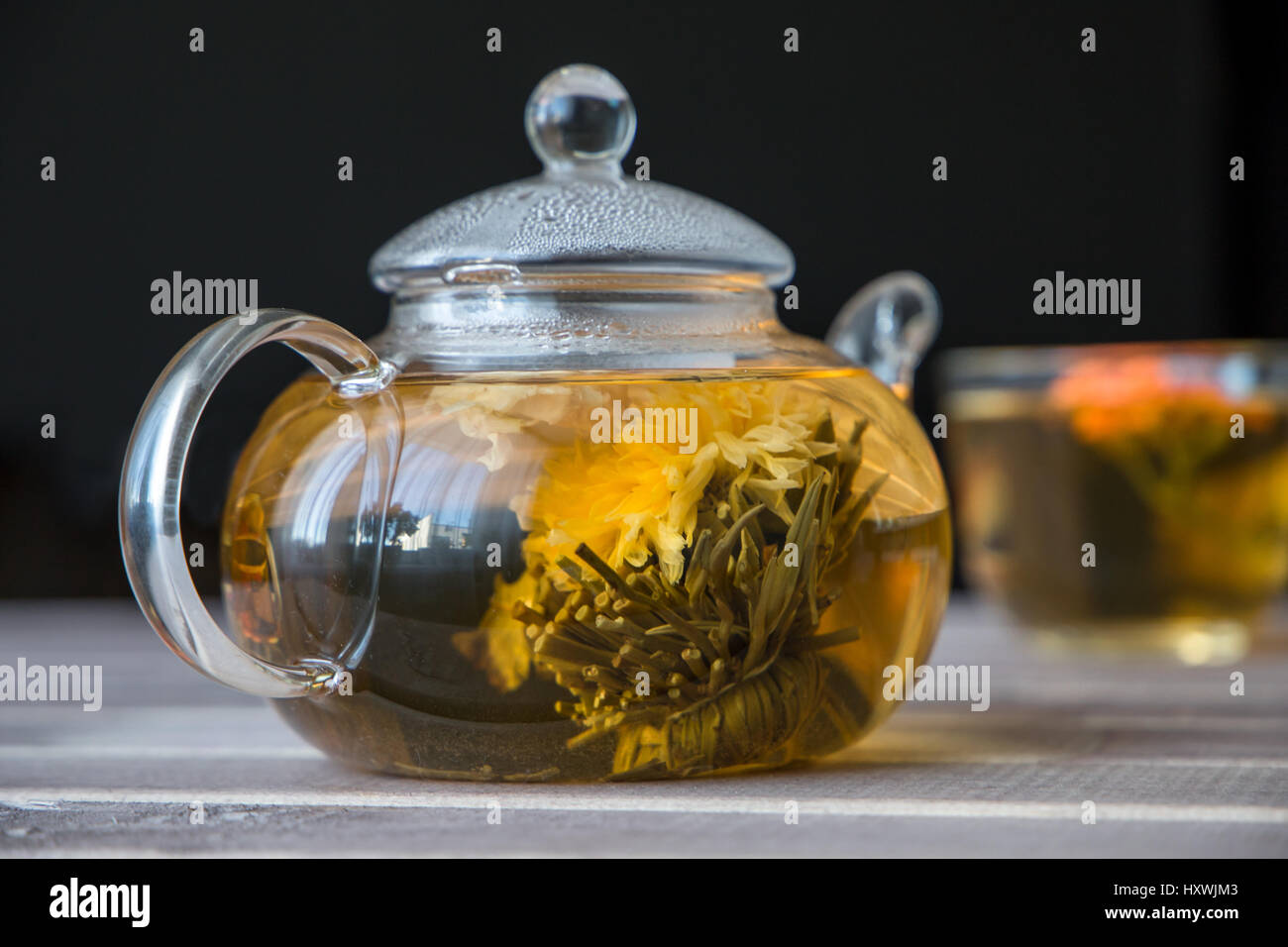 a glass tea pot with Flower Chinese tea and a cap of green tea on ...