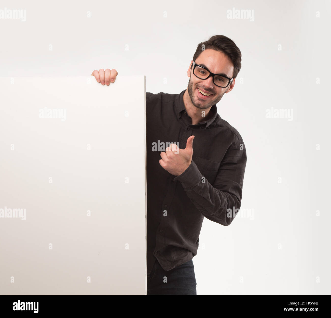 Young happy man showing presentation, pointing on placard over gray ...