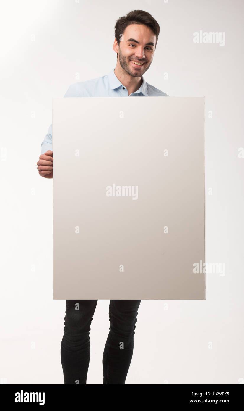 Young happy man showing presentation, pointing on placard over gray ...