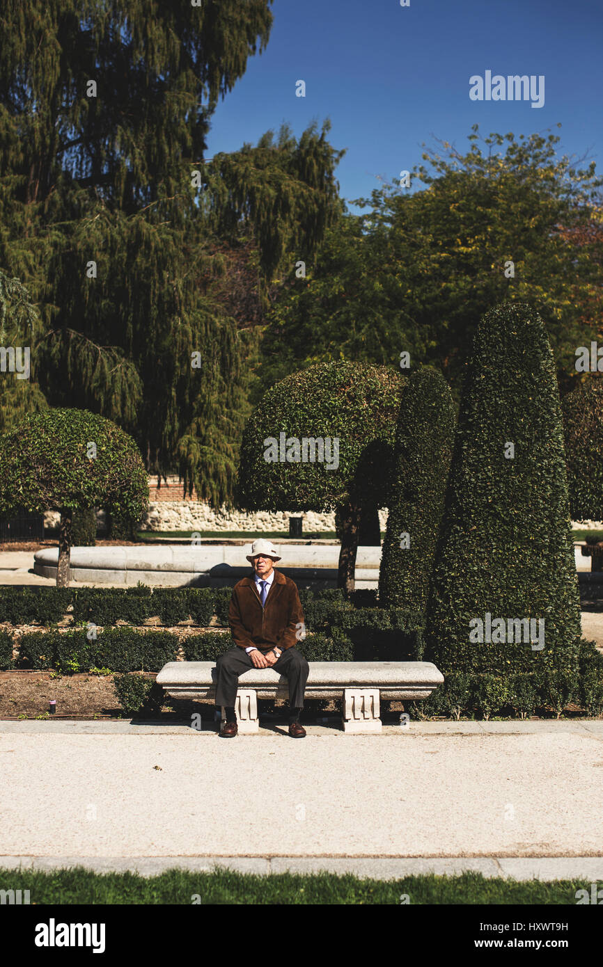 An old Spanish man is sitting on a bench in a park in Madrid, Spain ...