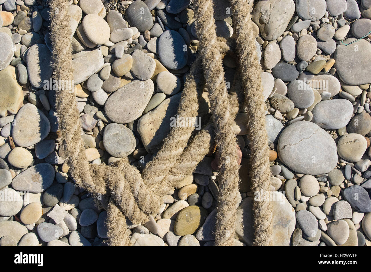 old worn battered marine rope on the pebble beach on a Sunny summer day ...