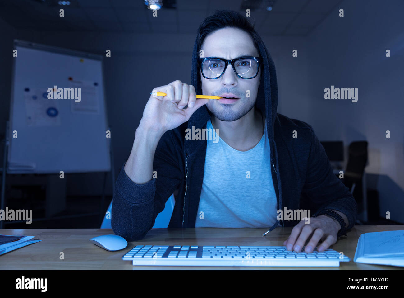 Handsome thoughtful hacker breaking into a website Stock Photo - Alamy