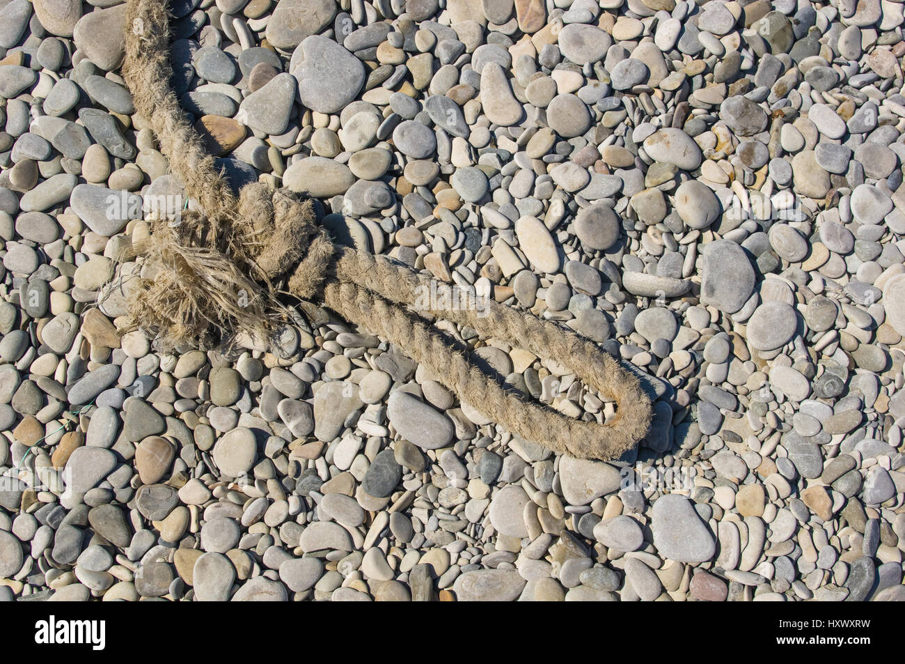 old worn battered marine rope on the pebble beach on a Sunny summer day ...