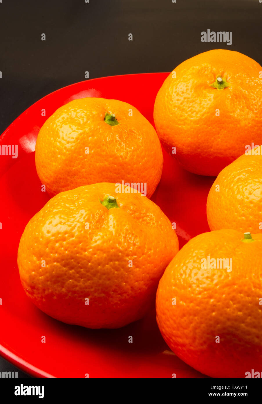 tangerines in a red plate on black background Stock Photo - Alamy