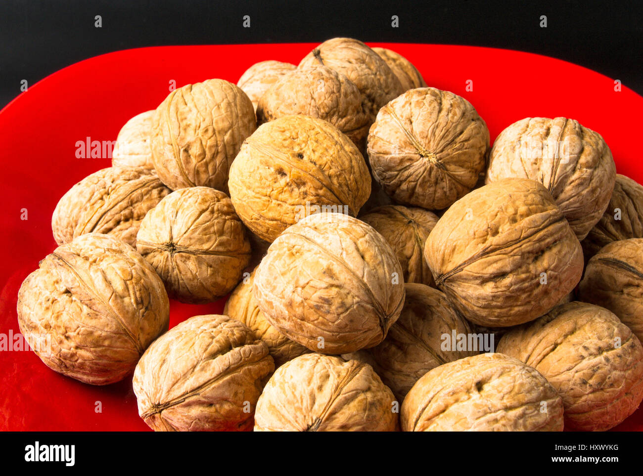 walnuts in red plate on black background Stock Photo - Alamy