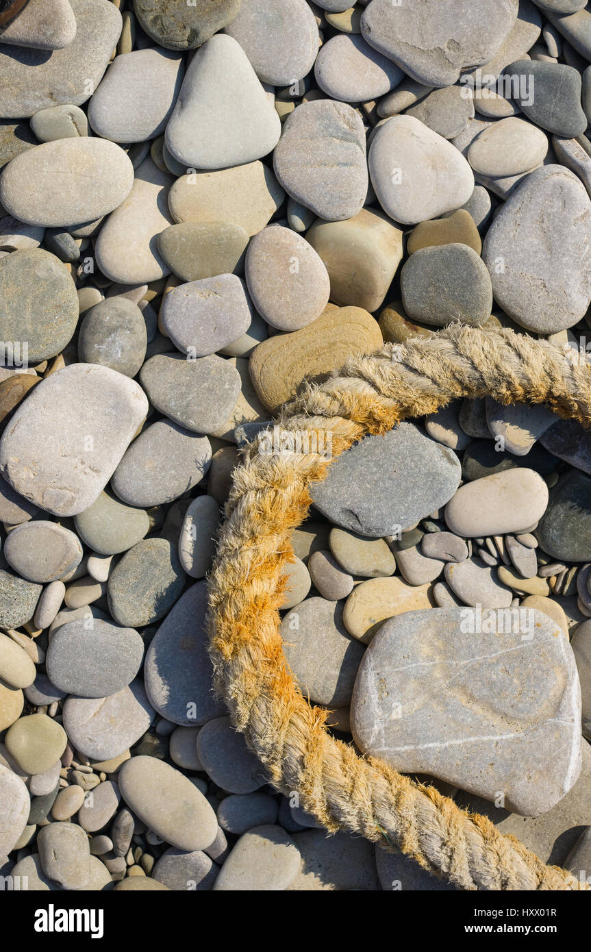 old worn battered marine rope on the pebble beach on a Sunny summer day ...
