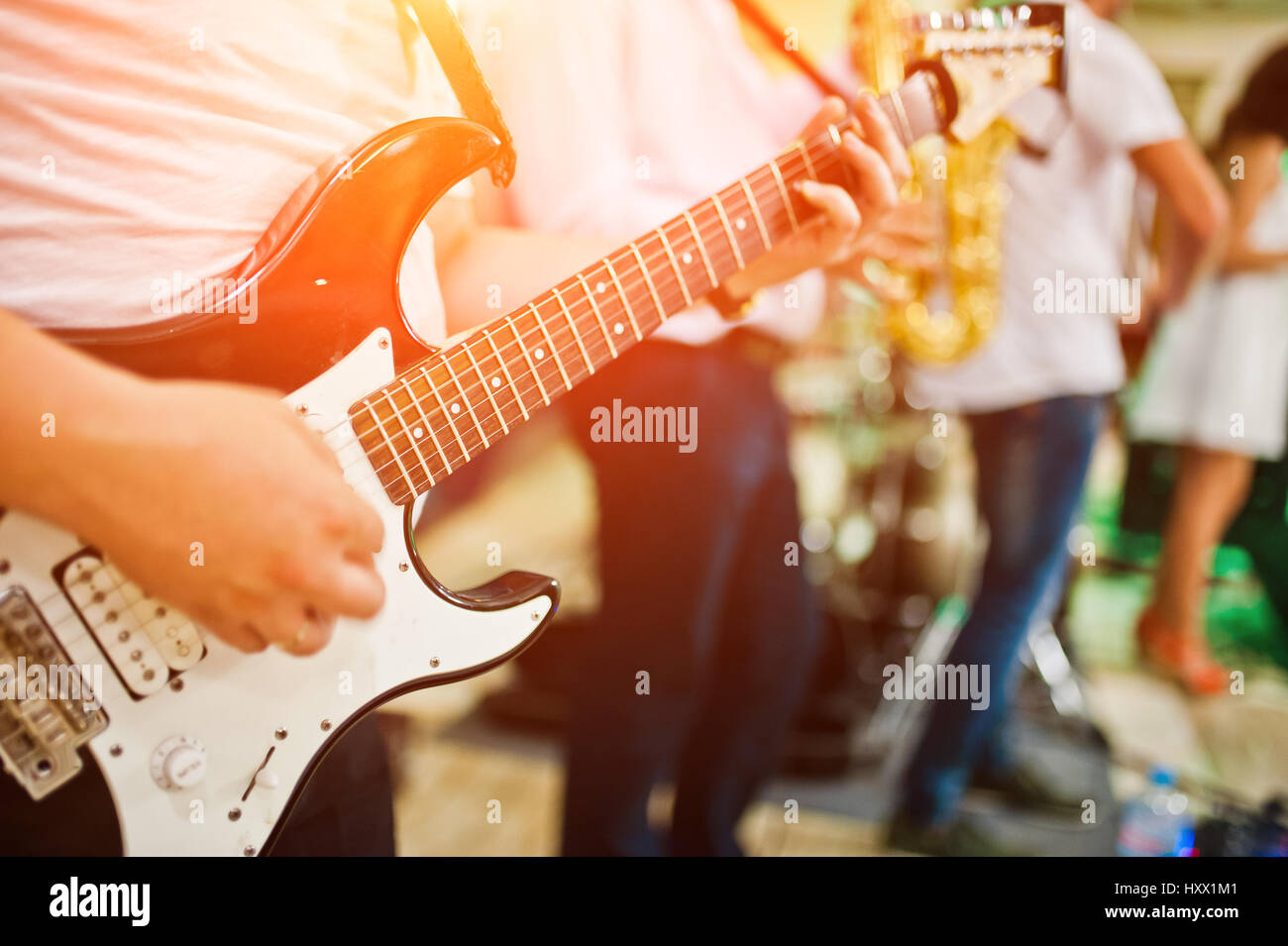 Man playing on electric guitar against band Stock Photo - Alamy