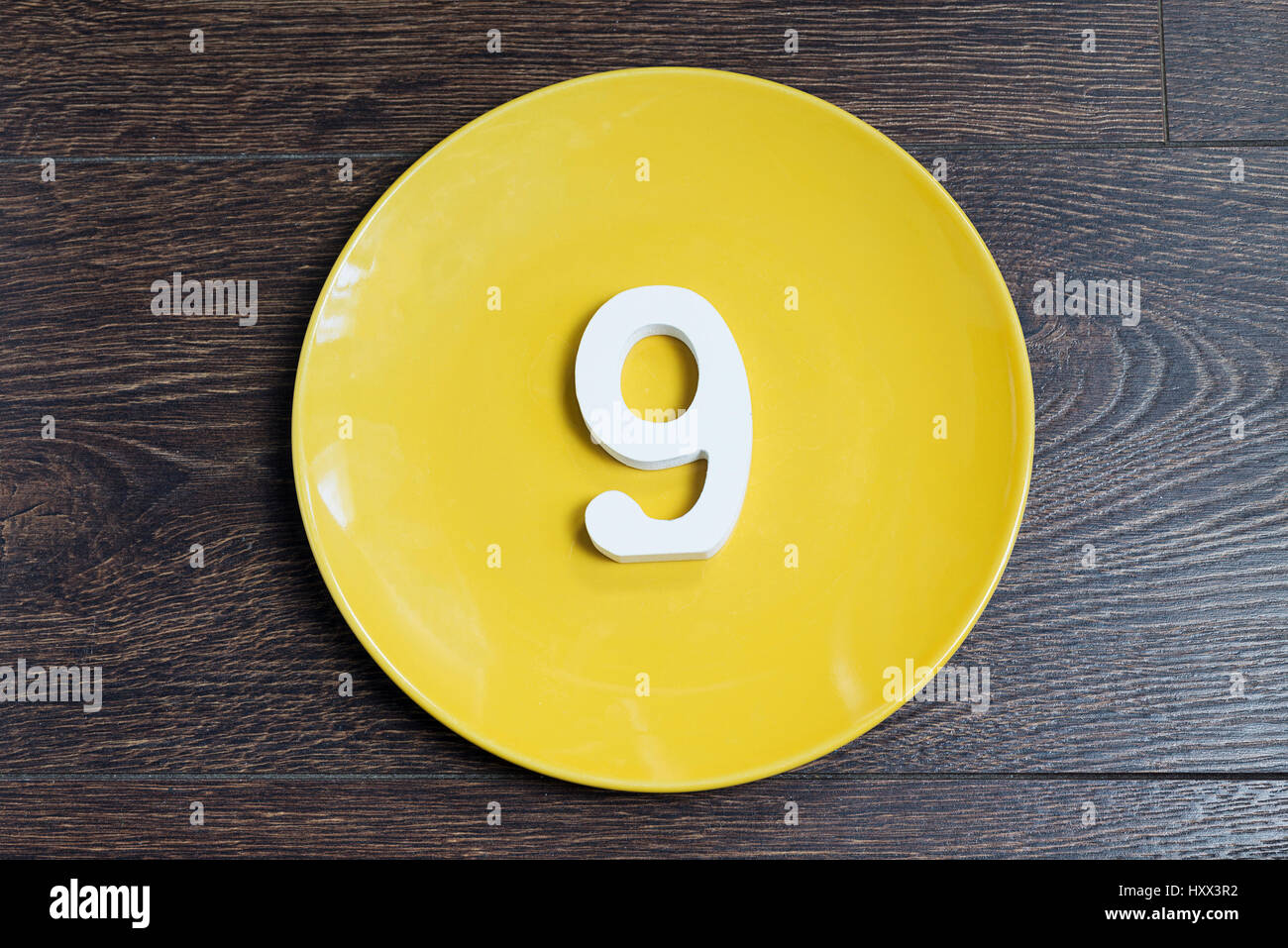 Number nine on the yellow plate and brown background Stock Photo - Alamy