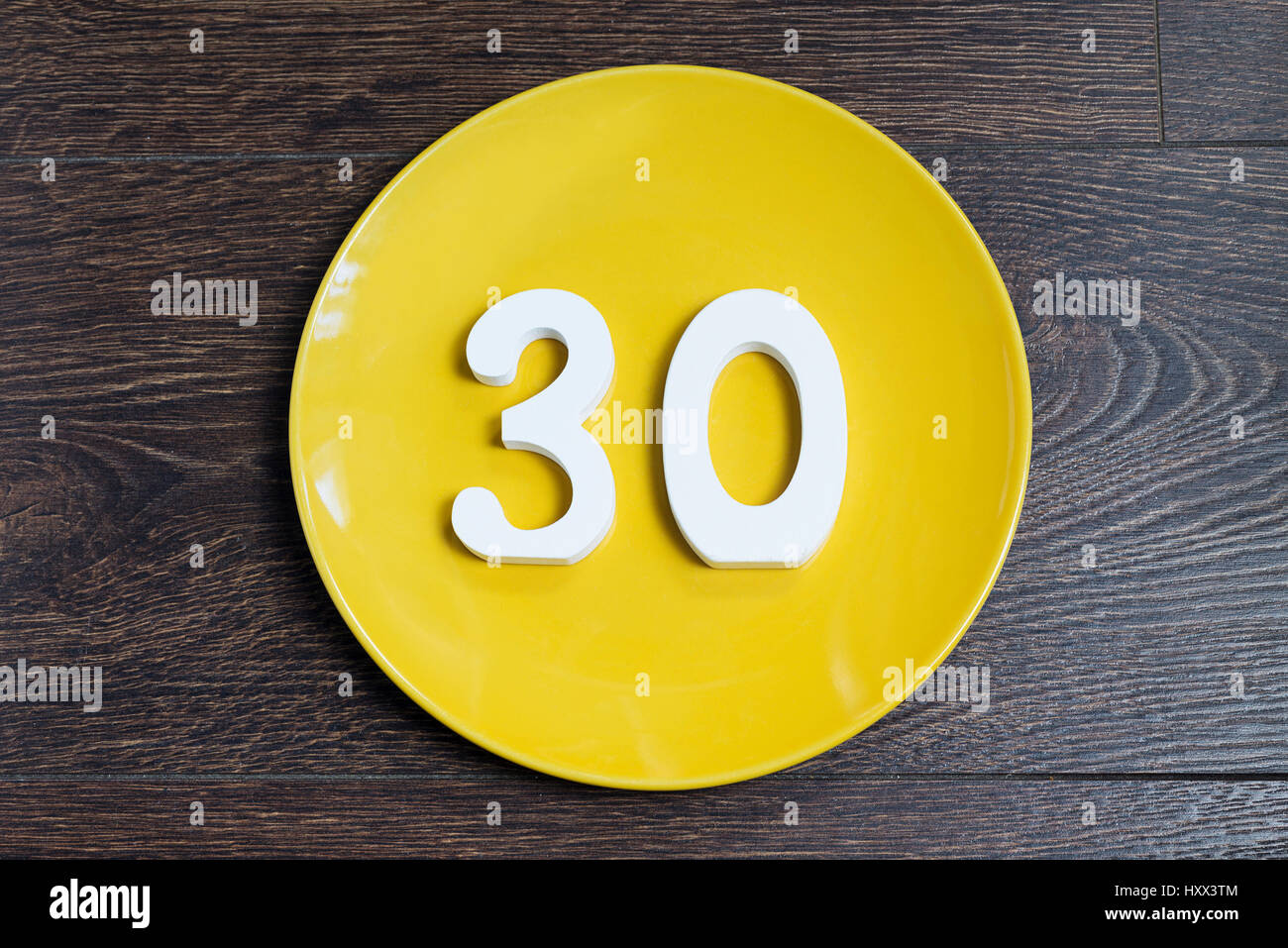 The number thirty on yellow plate and brown background Stock Photo - Alamy