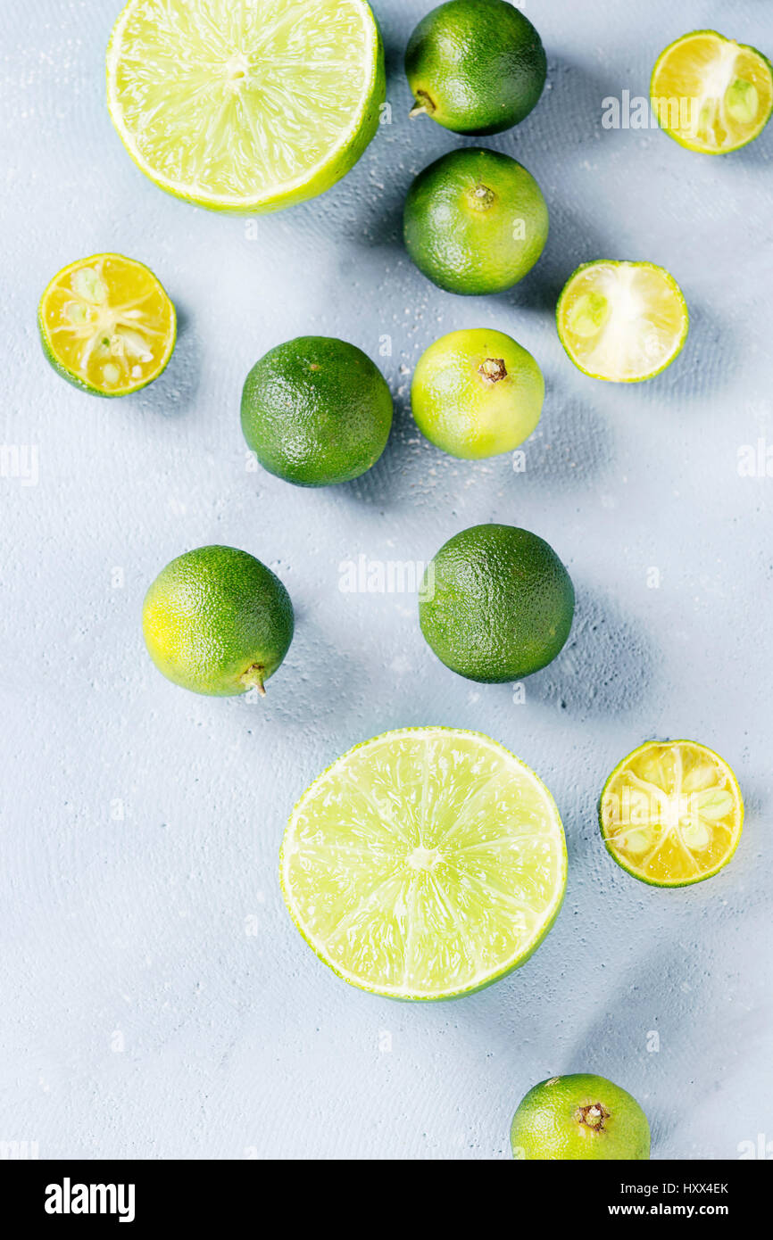 Whole, sliced lime and mini limes over gray stone texture background ...