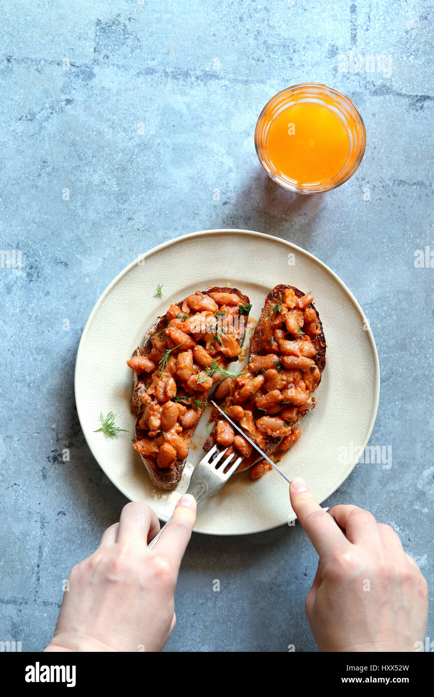 Female eating beans on toast served with a glass of orange juice Stock ...