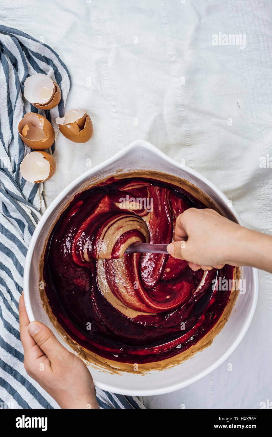 A woman mixing a red velvet cake batter in a large bowl photographed ...