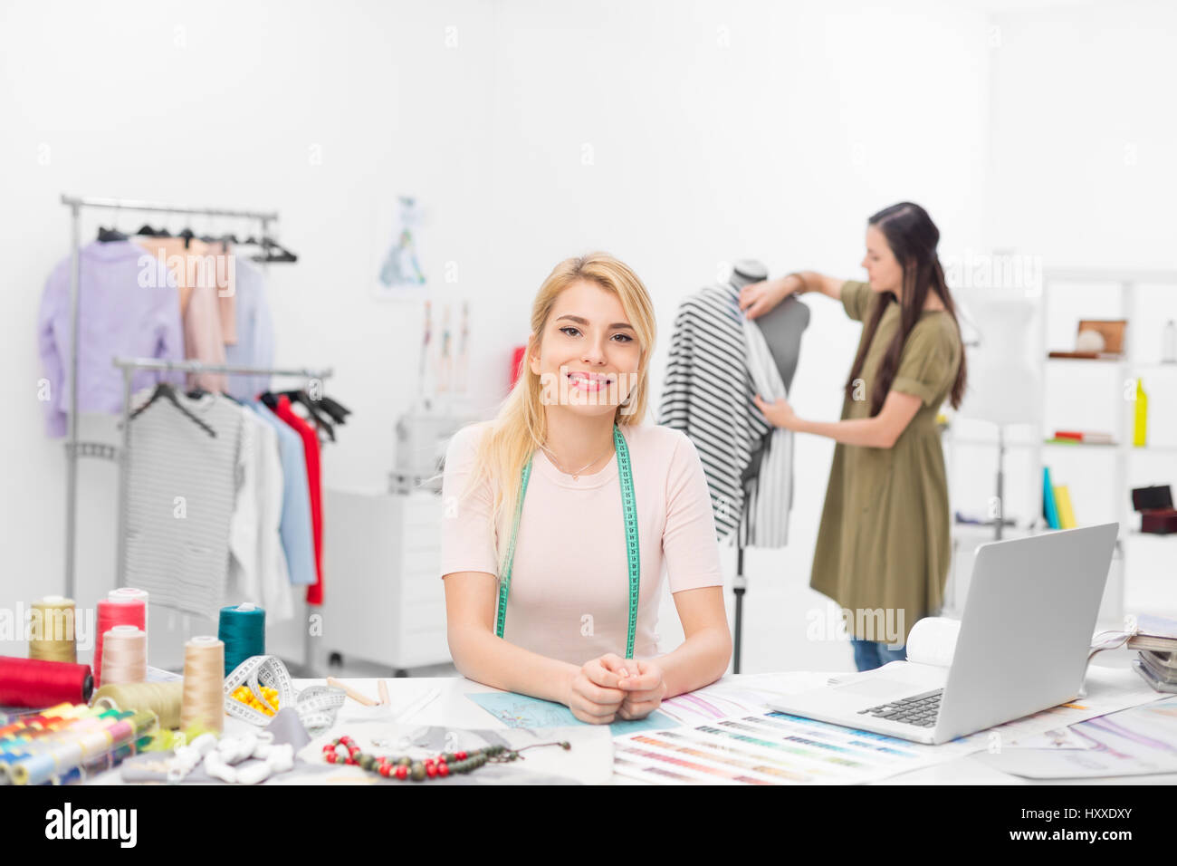 happy young fashion designer sitting at the desk and coworker in ...