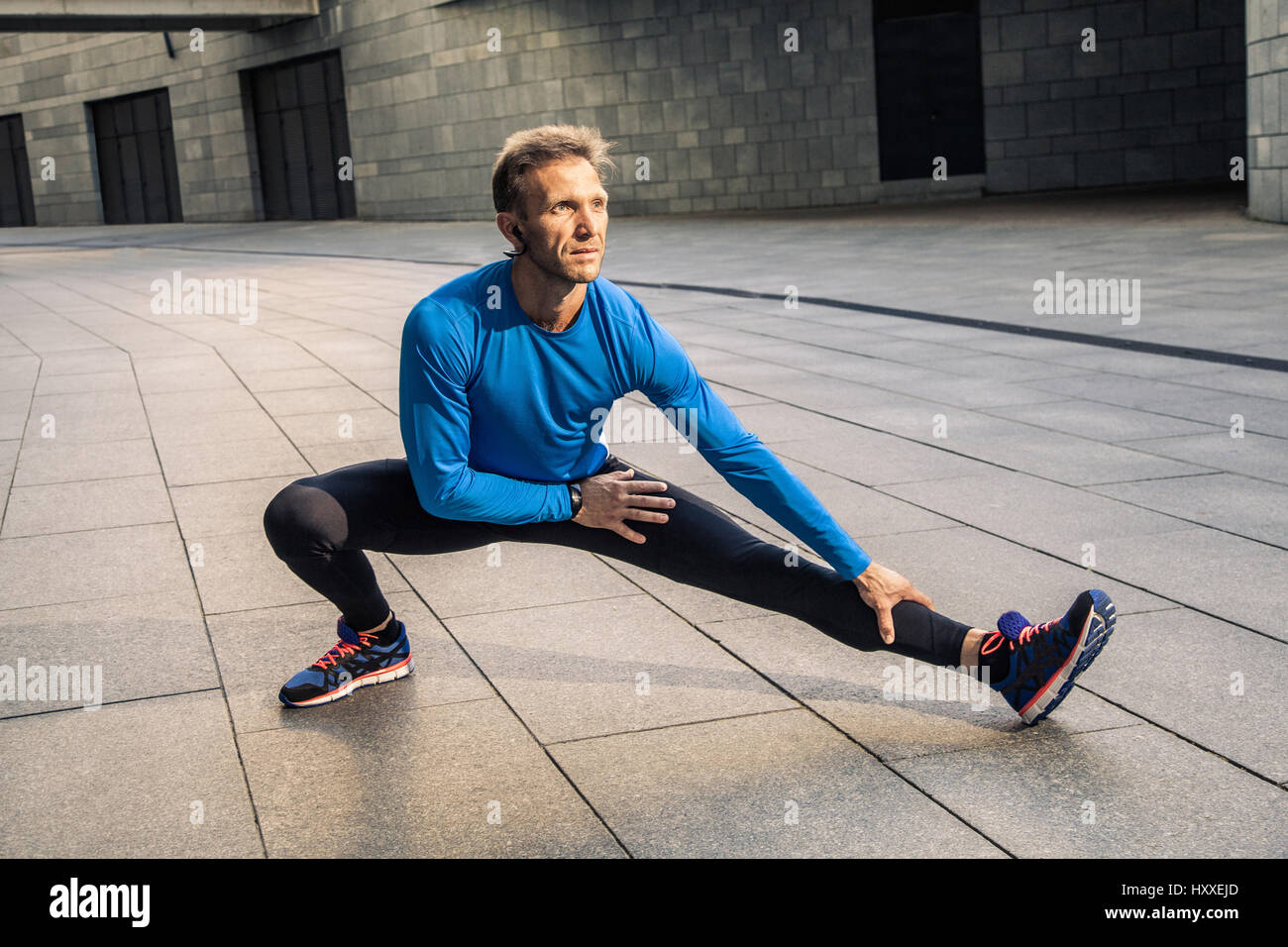 Handsome athlete man in black blue sport uniform stretching body ...