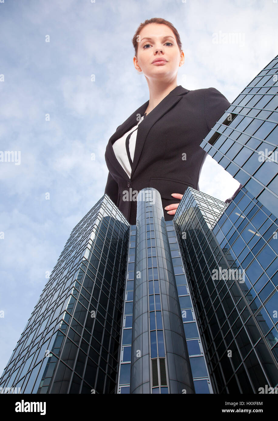 Giant young businesswoman standing behind office building Stock Photo ...