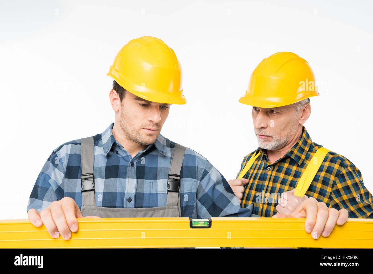 Two serious workmen working with level tool on white Stock Photo - Alamy