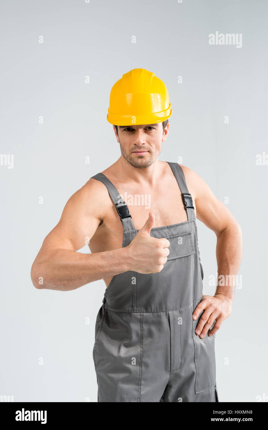 Handsome professional male builder showing thumb up on grey Stock Photo ...
