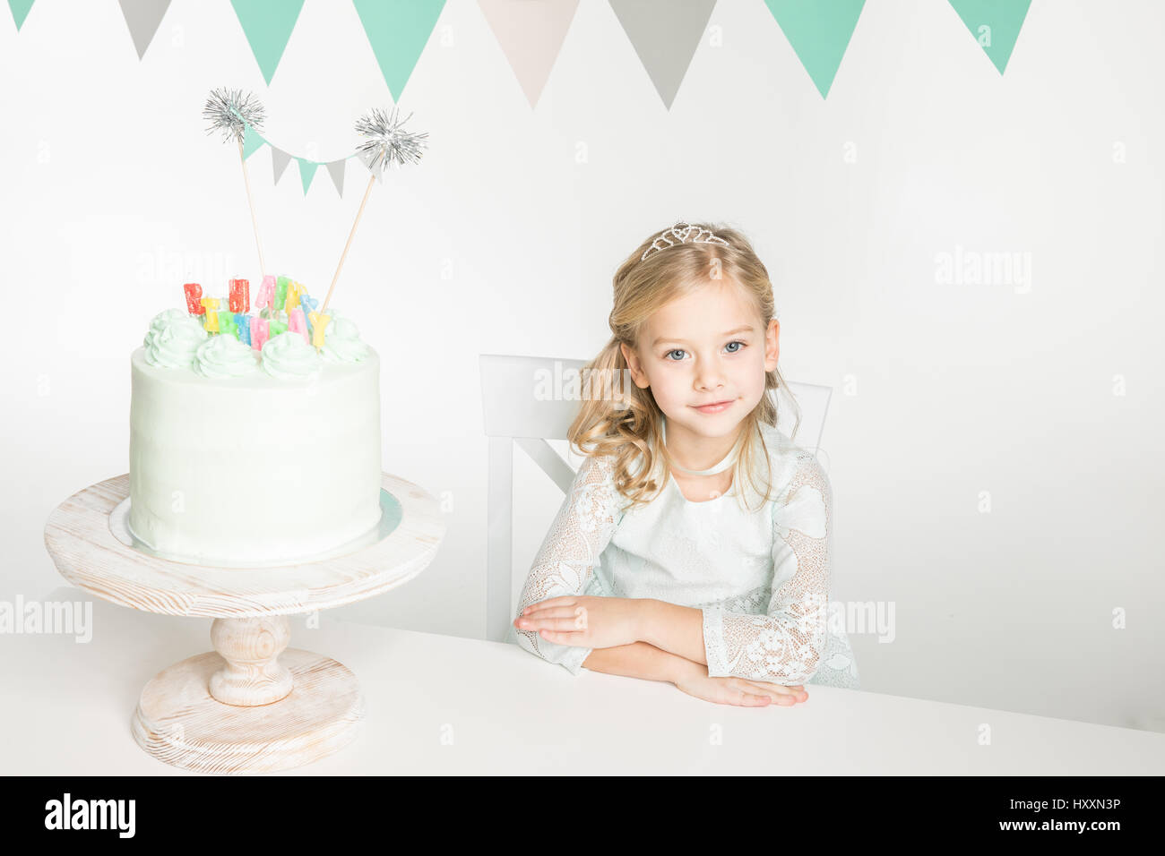 Adorable little girl sitting at festive table with birthday cake Stock ...