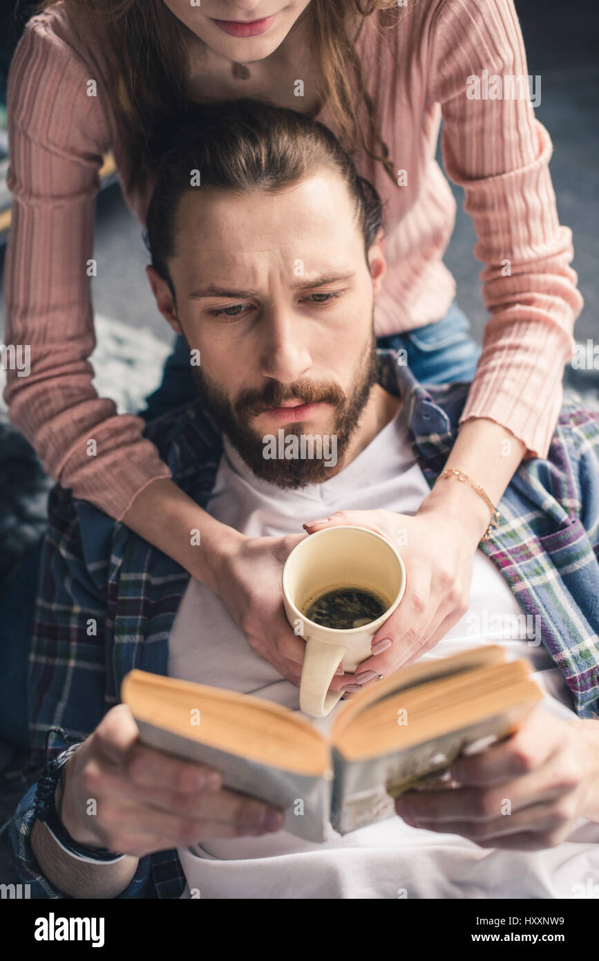 Young couple reading book together while drinking coffee Stock Photo ...