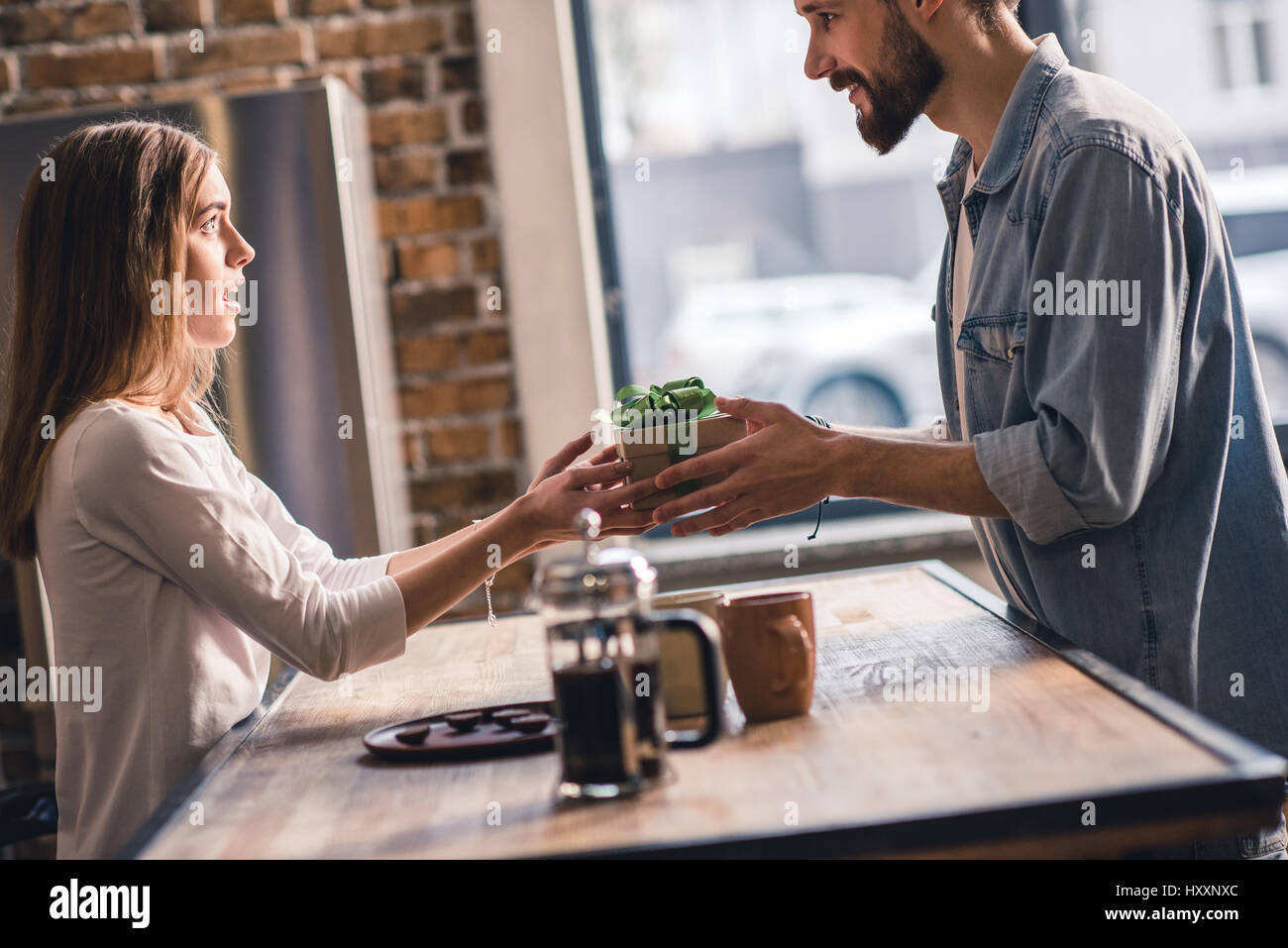 Handsome young man giving gift box to surprised woman Stock Photo - Alamy