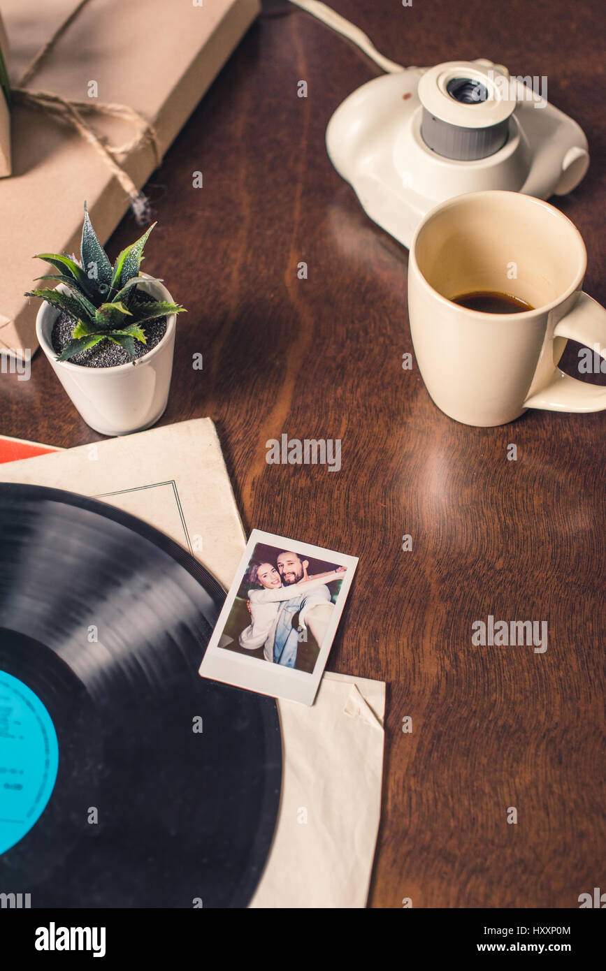 Composition of vynil record and instant photo, camera and coffe cup on ...