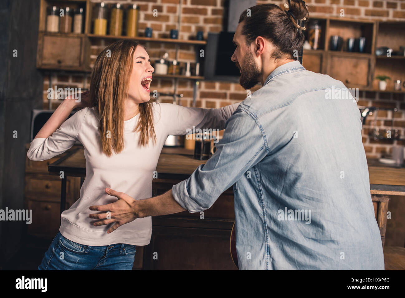 Young angry woman trying to hit a man in the kitchen Stock Photo - Alamy