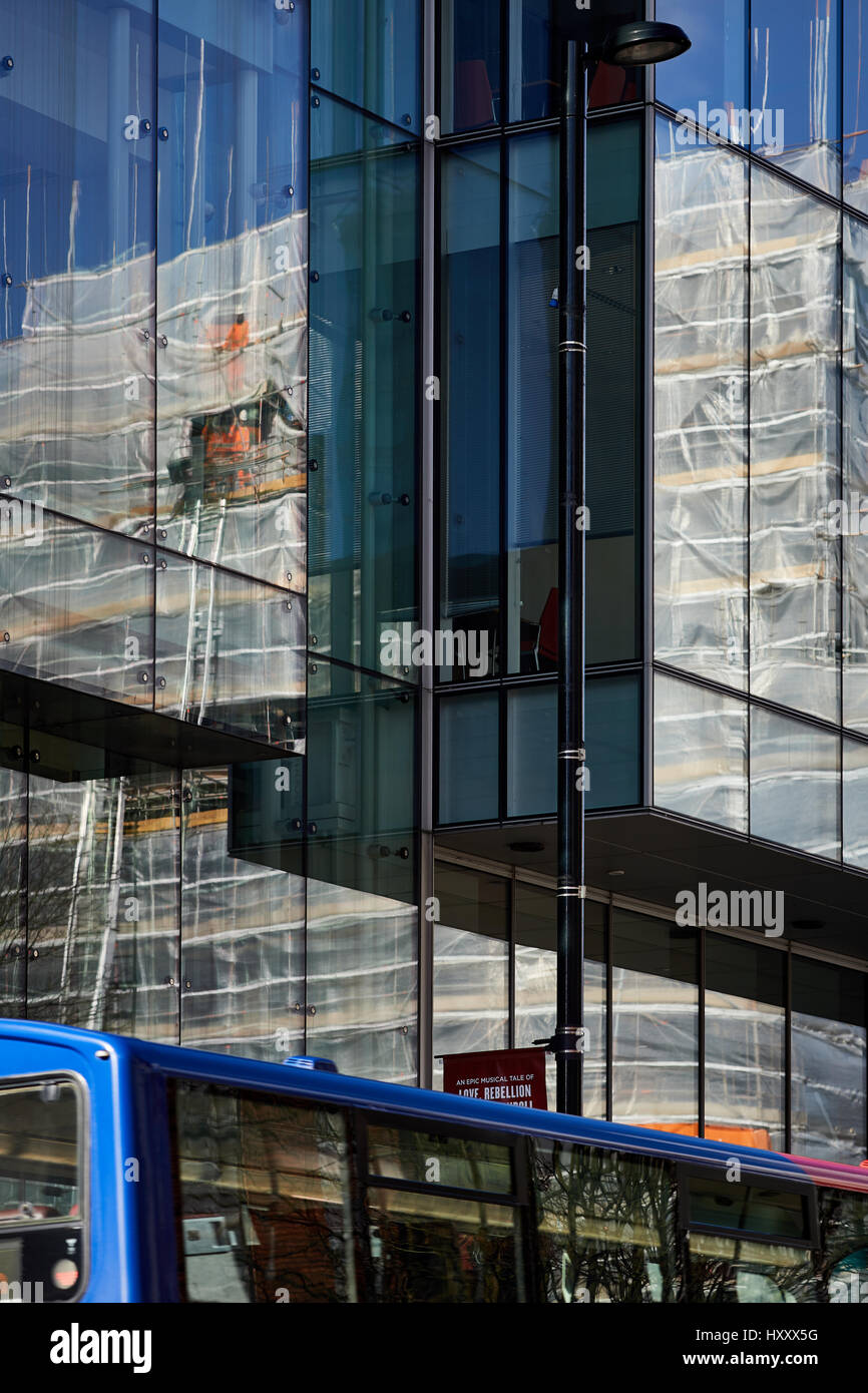 Reflection of construction workers erecting scaffolding on an office ...