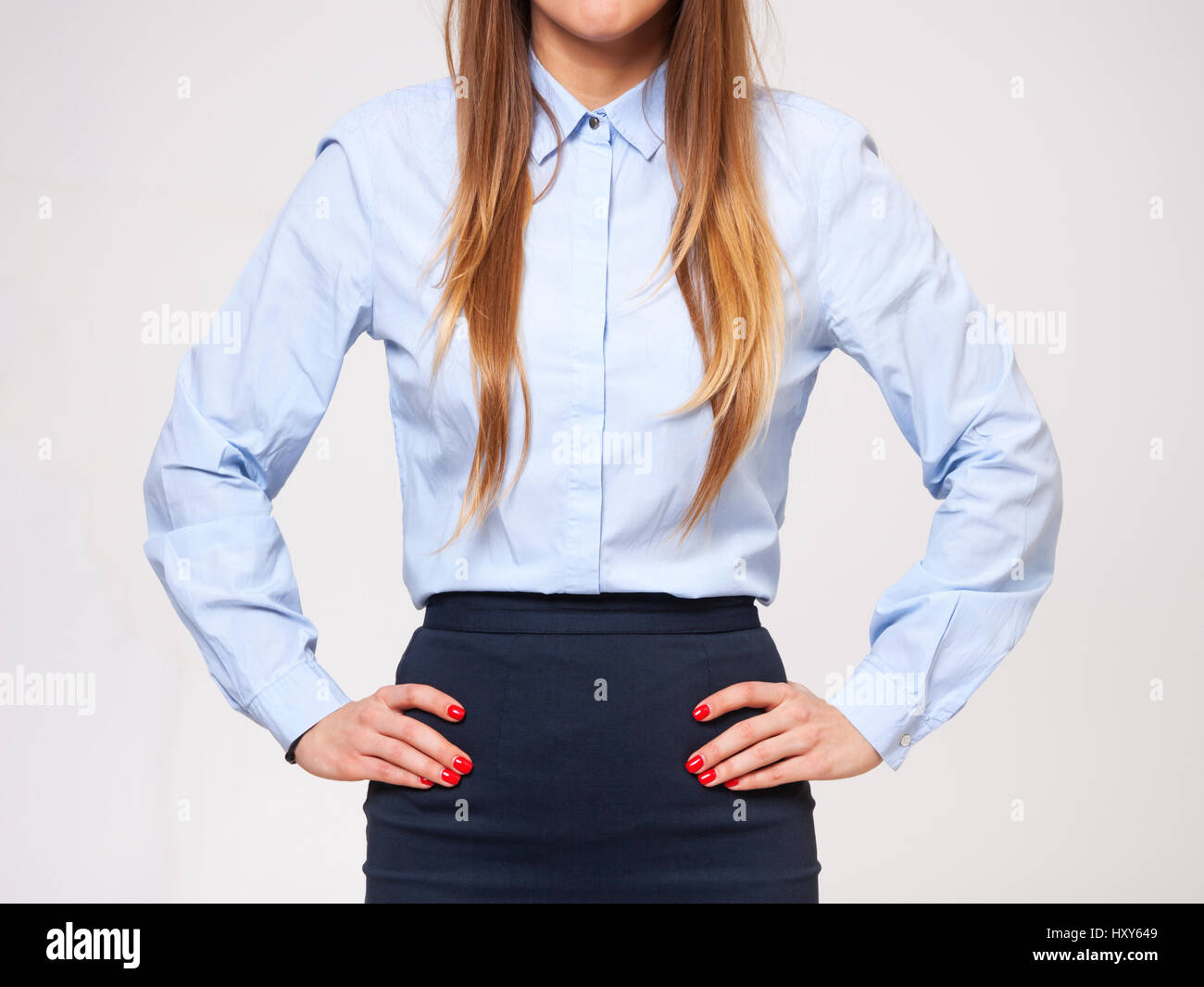 Midsection of young business woman standing in formal blue shirt and ...