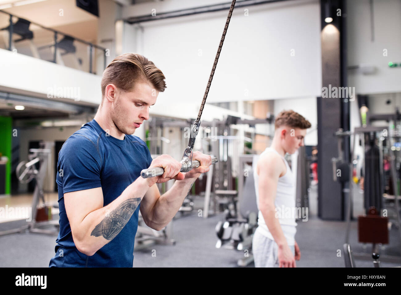 Young handsome fit man working out on pull-down machine in gym ...