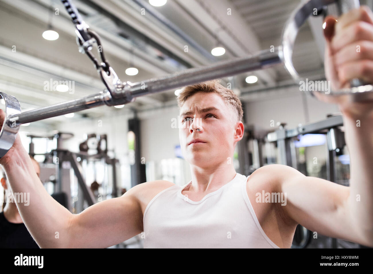 Young handsome fit man working out on pull-down machine in gym ...