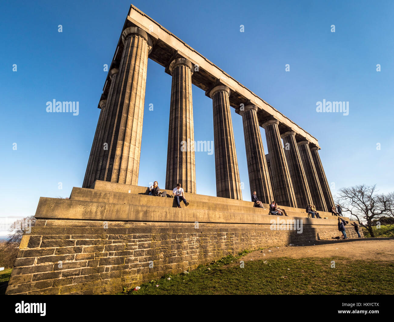Tourists sitting on the steps of the National Monument of Scotland ...