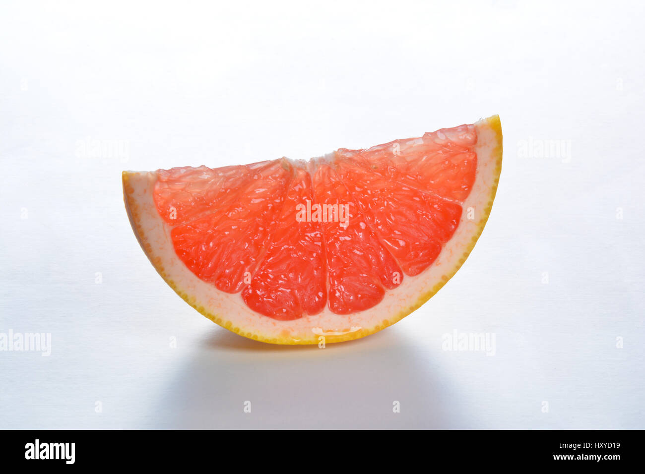 Closeup of a single slice of pink grapefruit on a white background ...
