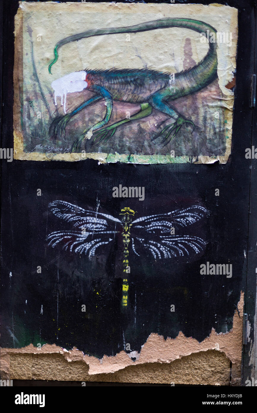 defaced poster of lizard above dragonfly graffiti Stock Photo - Alamy