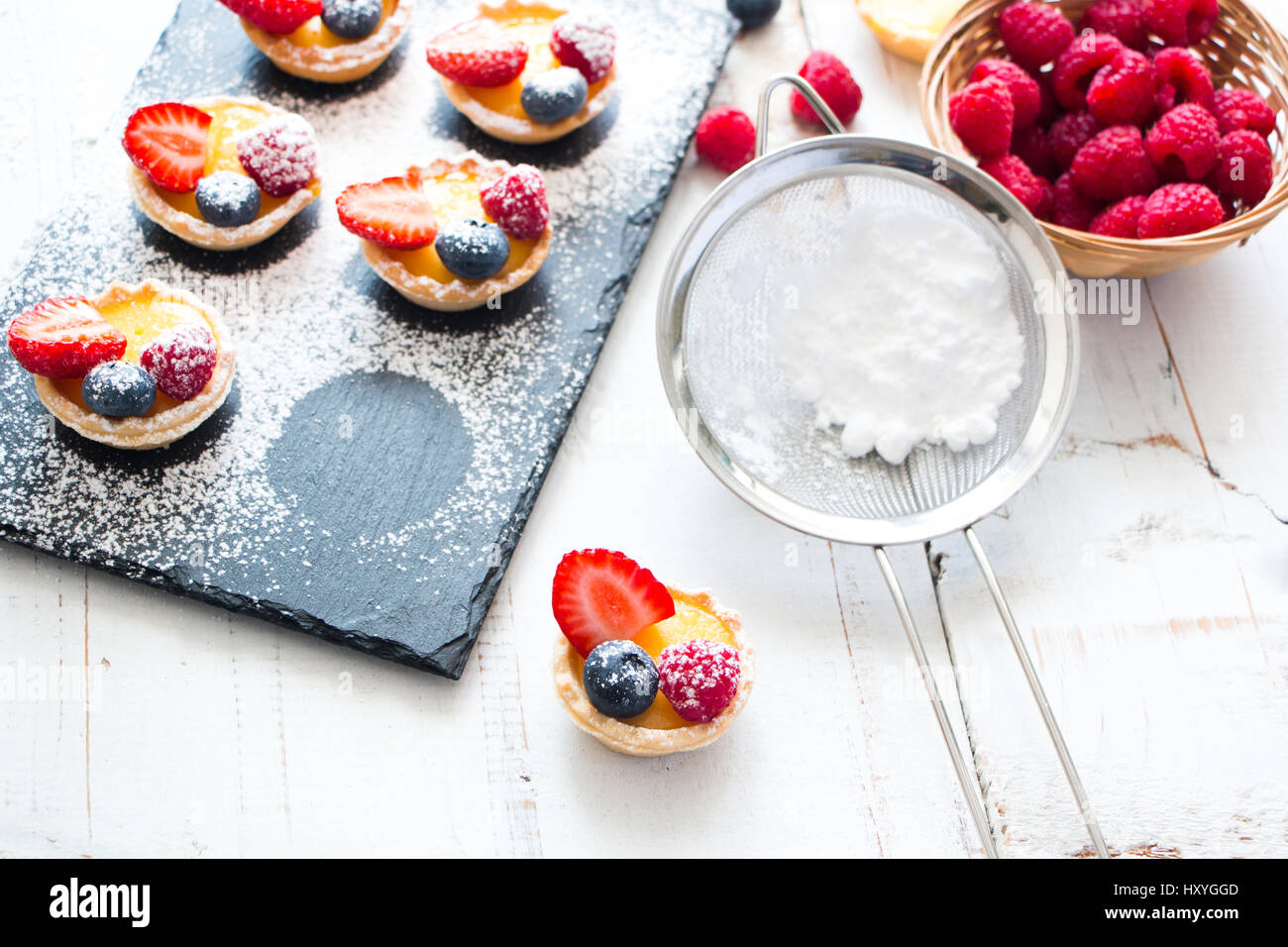 Preparing small pastry tartlets filled with vainila cream and fresh ...
