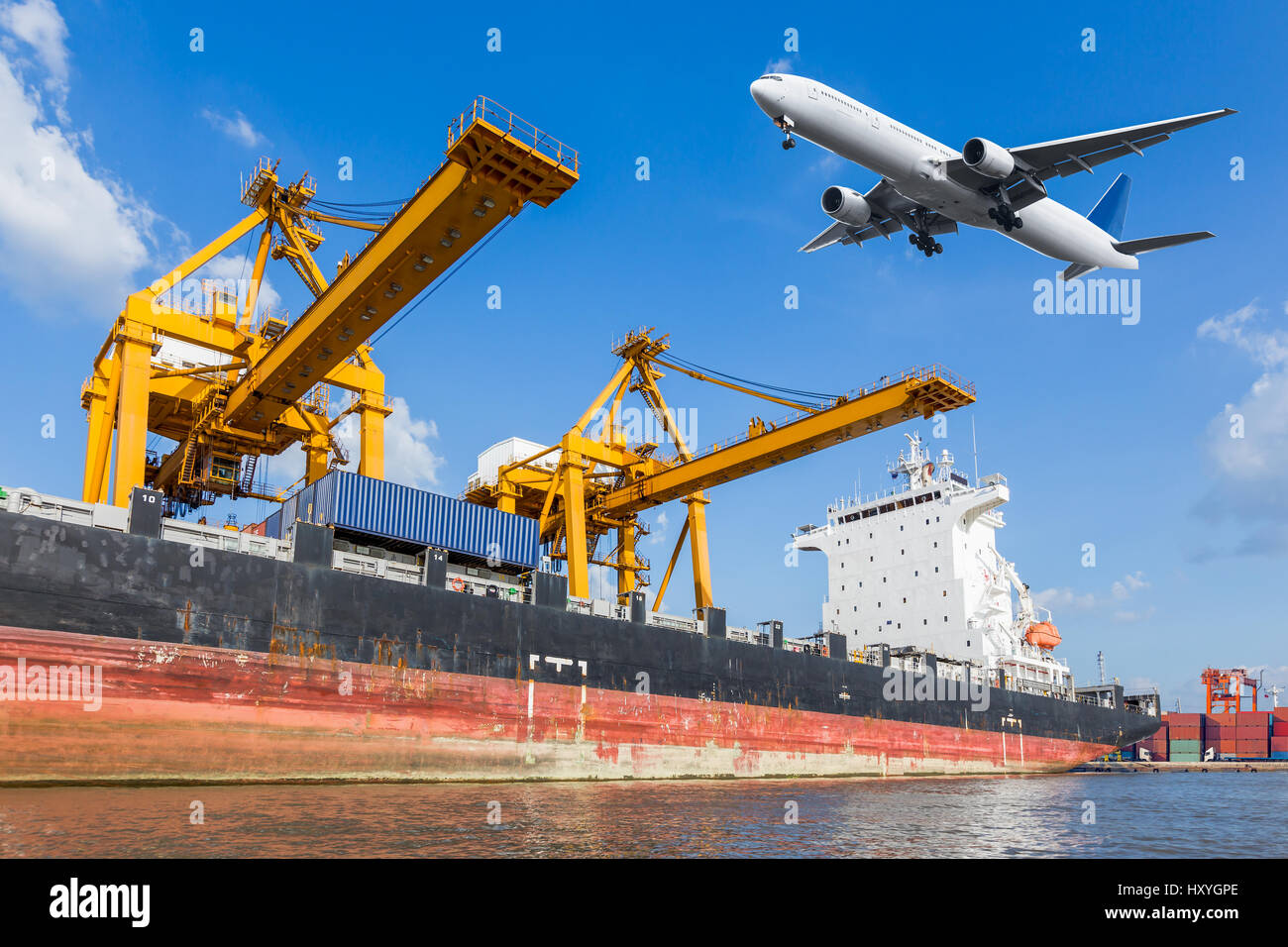 Cargo plane flying above ship port with working crane loading bridge in ...