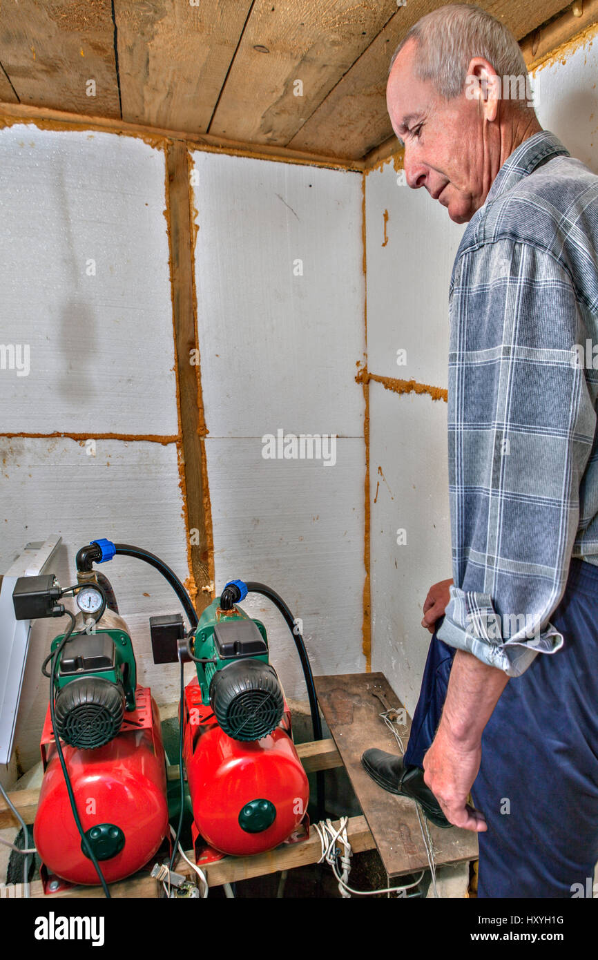 Water supply system farmhouse, peasant makes adjustment of pumps in the ...